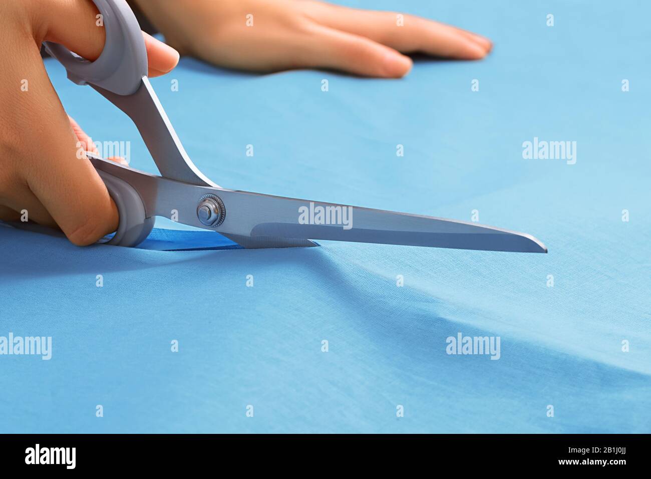 Close up side view of sewing scissors in the hands of a girl cutting ...