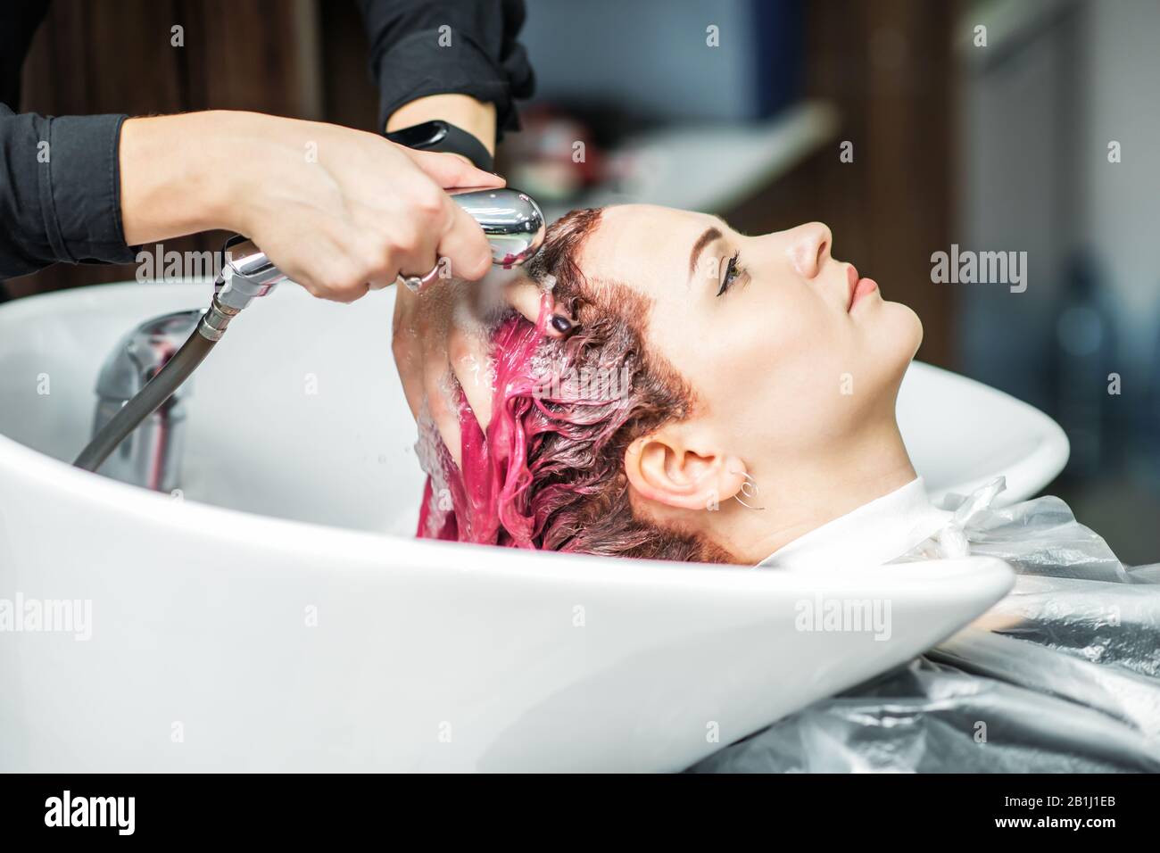 Hairdresser washing pink dyed hair of woman in sink, close up Stock ...