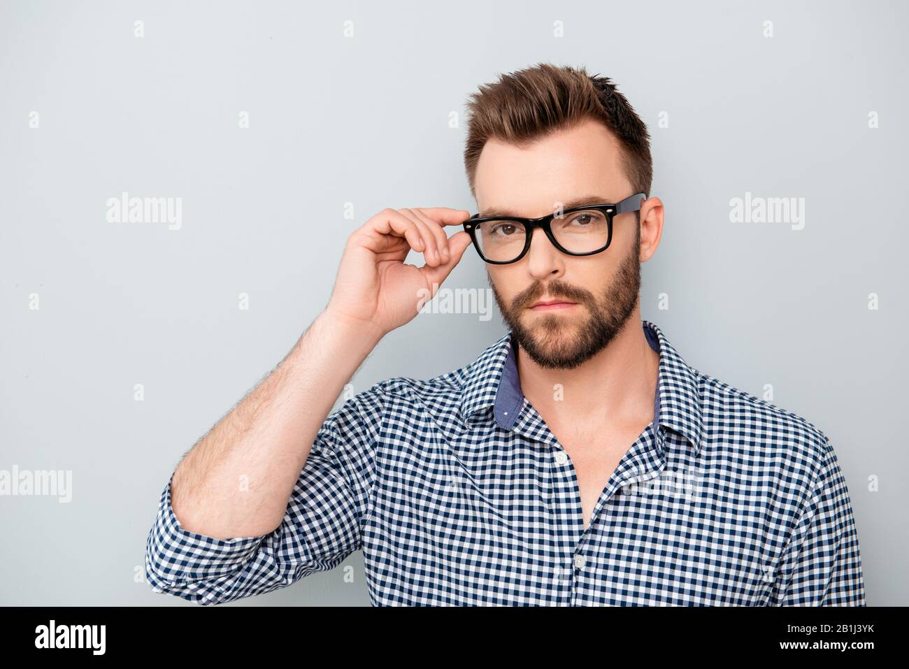 Serious minded young businessman touching his glasses Stock Photo - Alamy