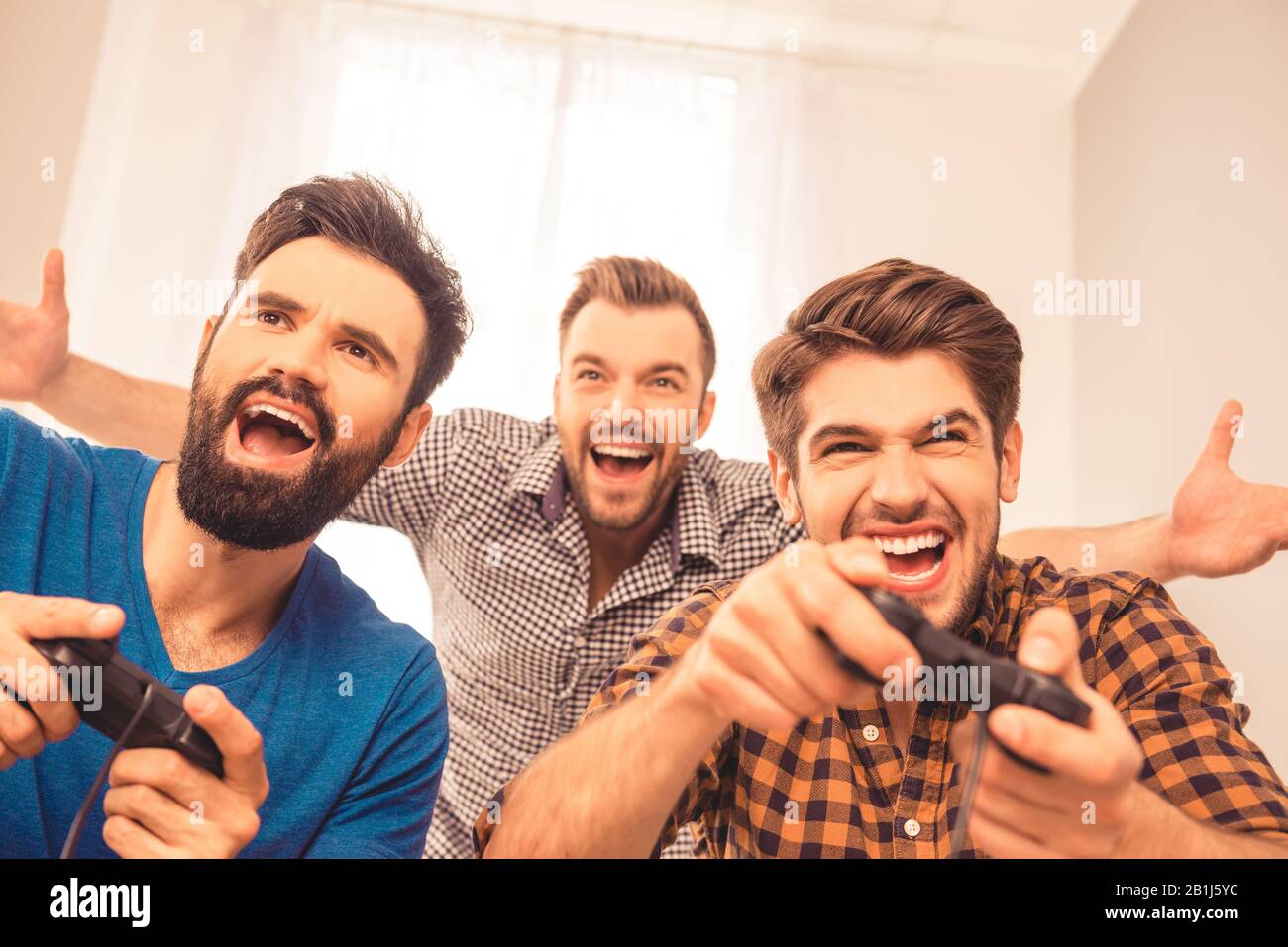 Portrait of excited laughing men playing video games Stock Photo - Alamy