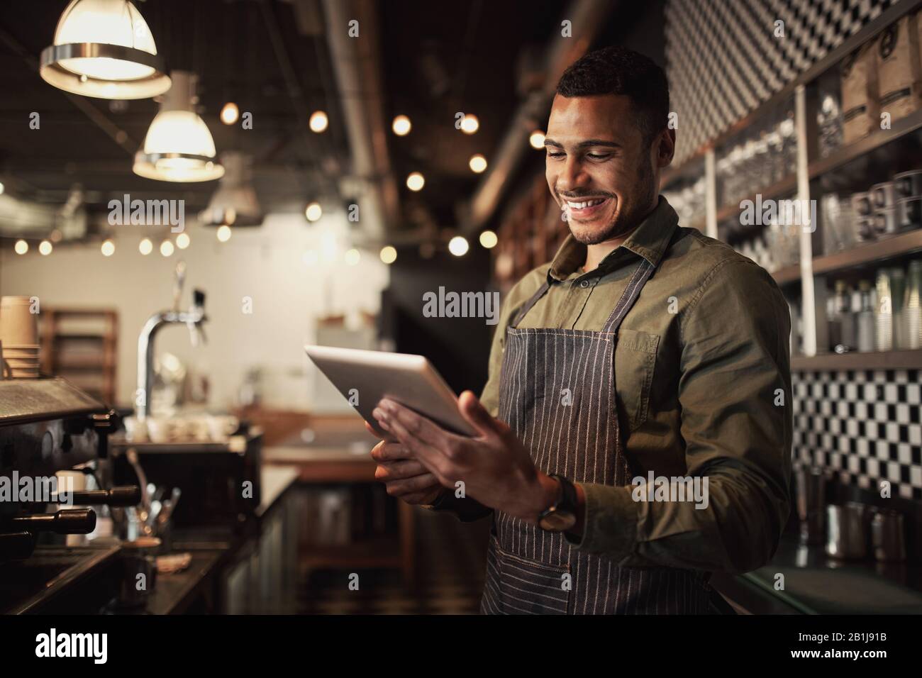 Portrait of successful young afro-american cafe owner standing behind ...