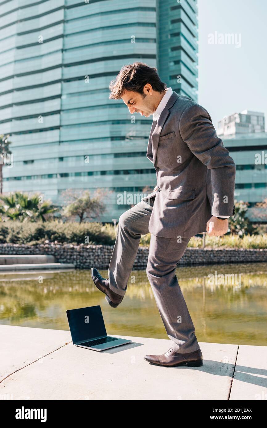 Frustrated businessman smashing his laptop outdoors Stock Photo - Alamy