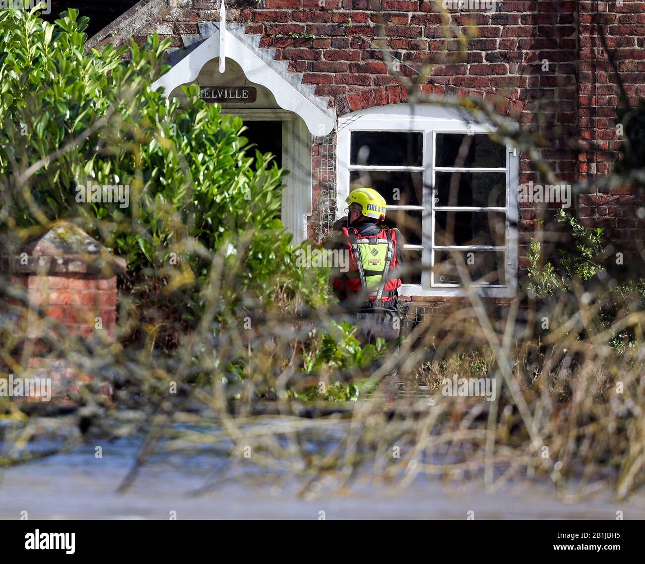 Fire and rescue personnel visit a property as flood water surrounds ...