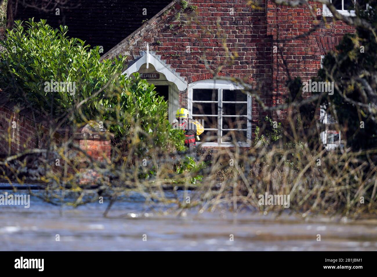 Fire and rescue personnel visit a property as flood water surrounds ...