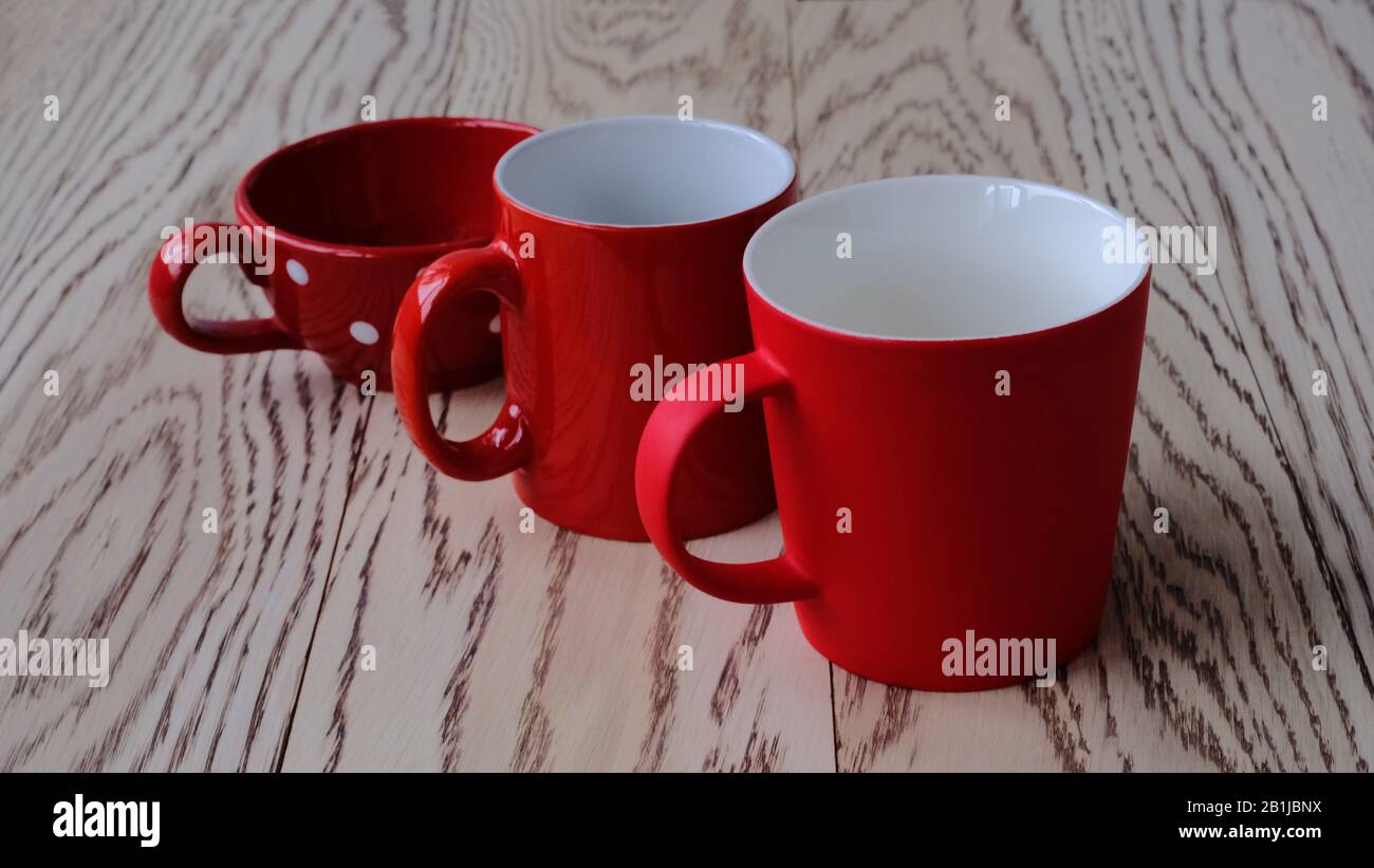 Three red cups of different shapes standing diagonally in a row on a ...