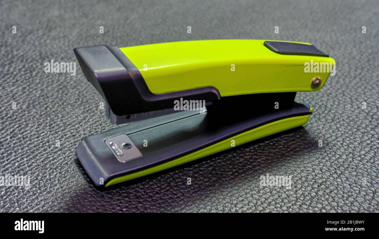 One green color stapler standing on a black leather surface Stock Photo ...