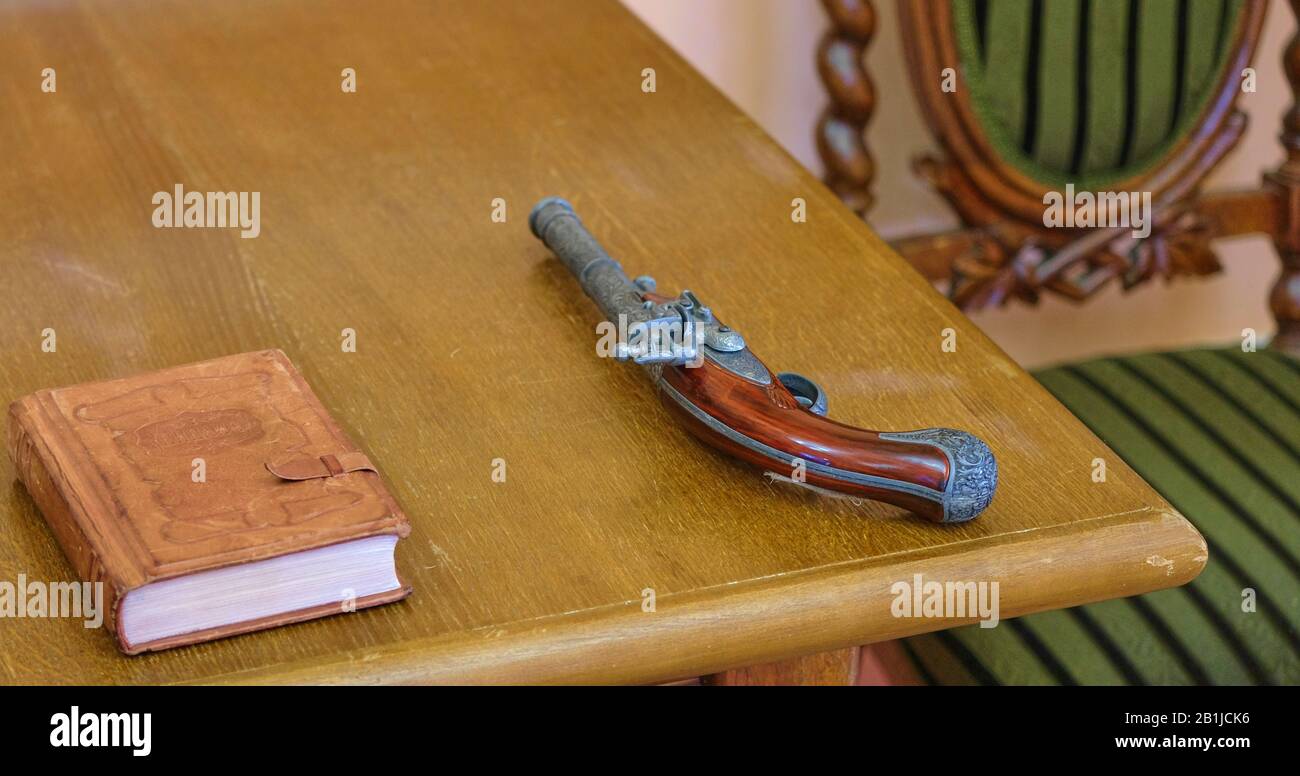 Old revolver lying on a table with a book on the background of an old ...