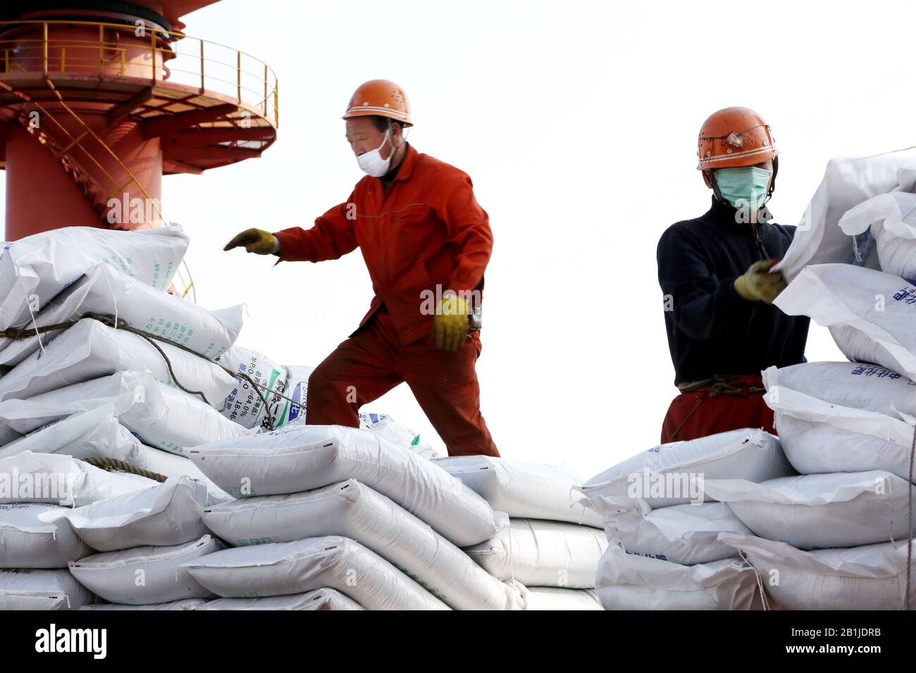 Chinese workers load a truck with sacks of imported fertilizer on the ...
