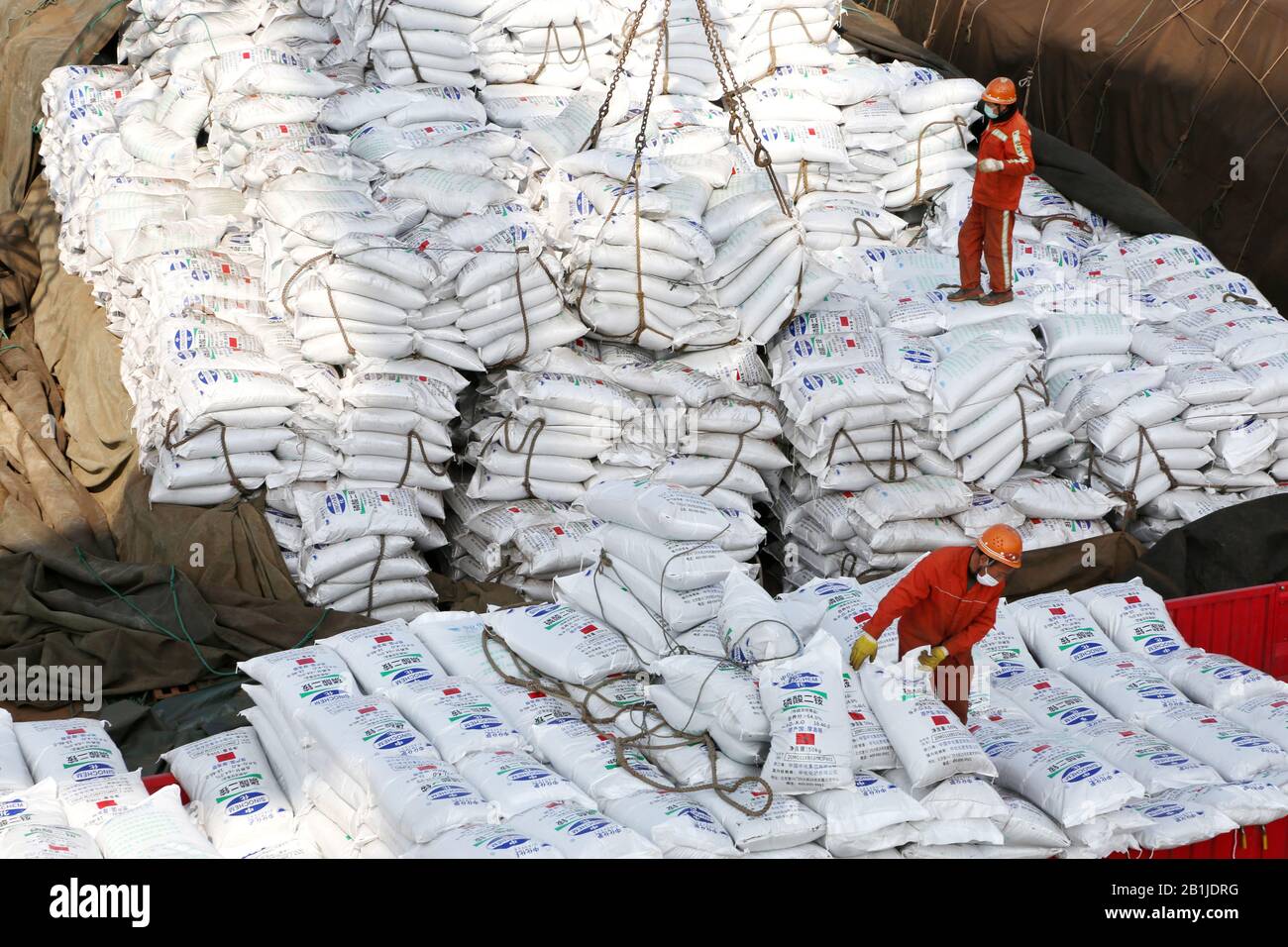 Chinese workers load a truck with sacks of imported fertilizer on the ...
