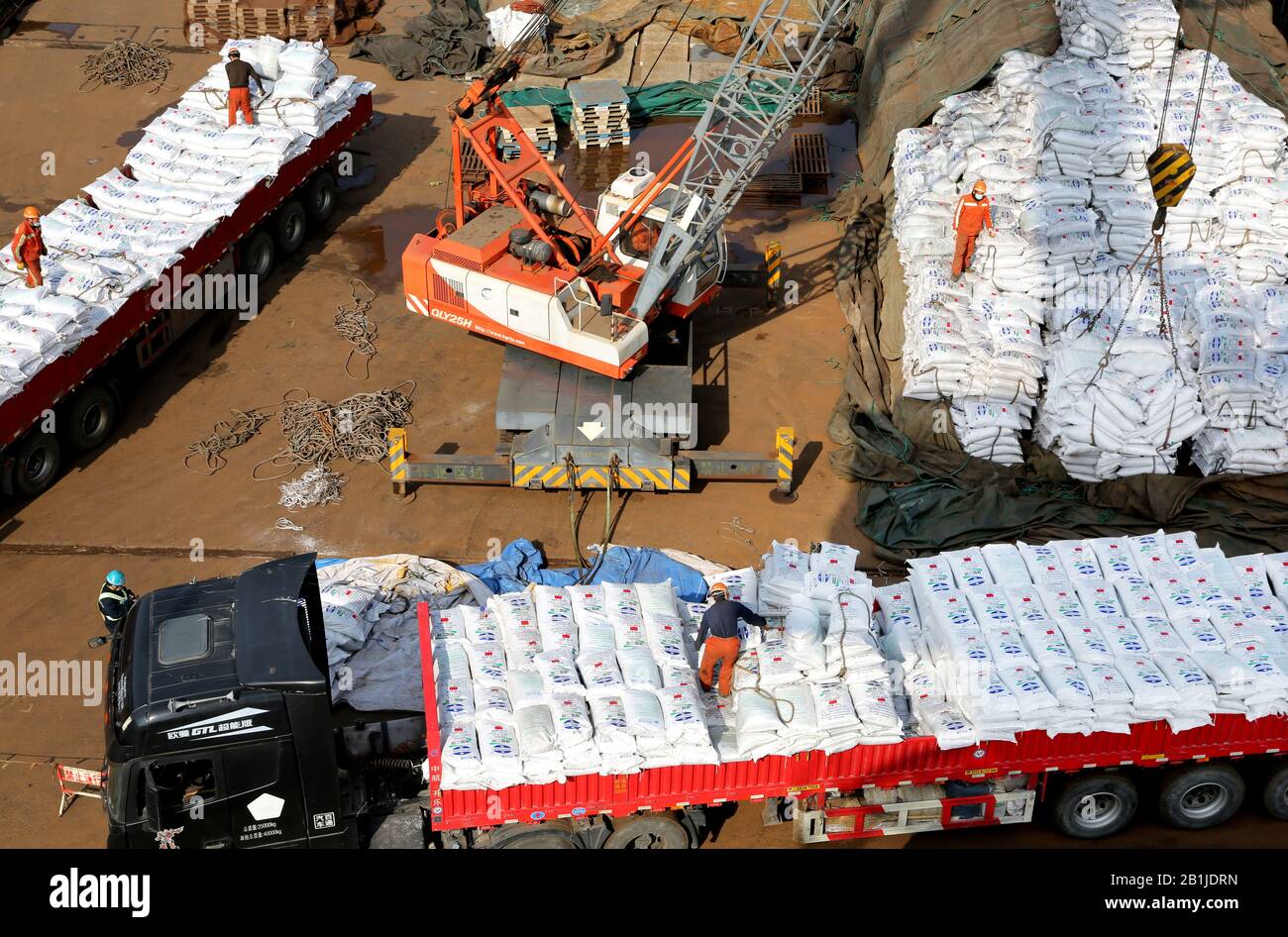 Chinese workers load a truck with sacks of imported fertilizer on the ...