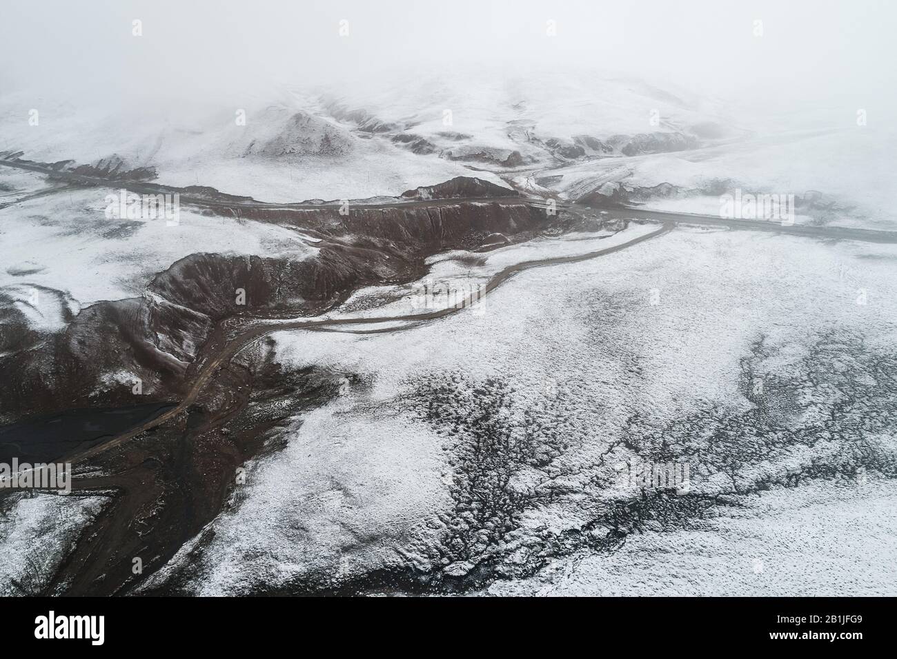 Country road winding through a valley surrounded by snowy mountains ...