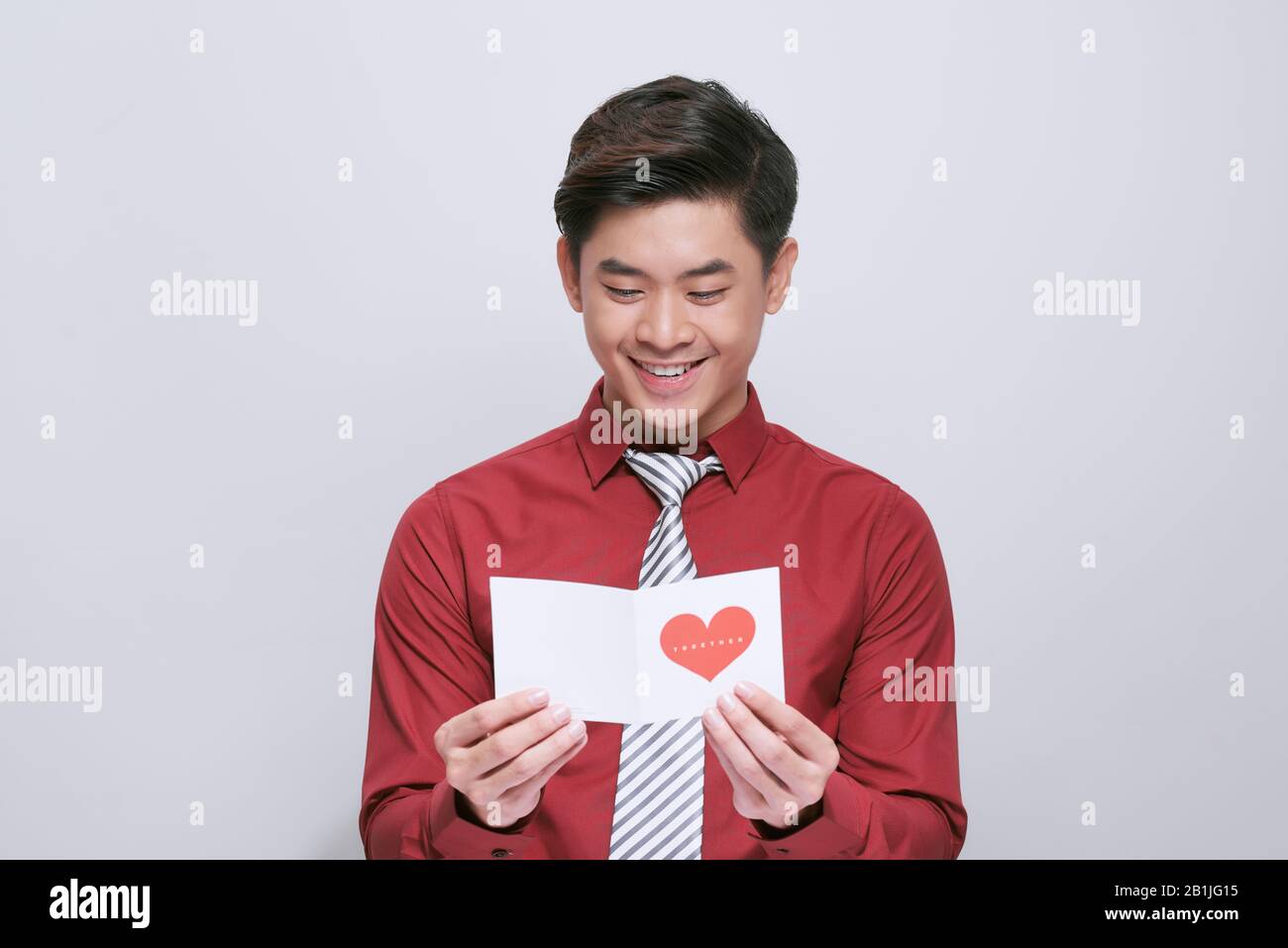 Handsome man with greeting card on light background. Valentine's Day ...