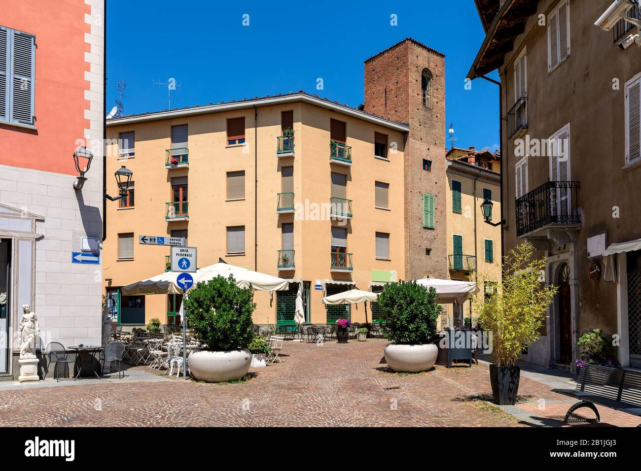 Small cobblestone square among old houses and medieval tower under blue ...