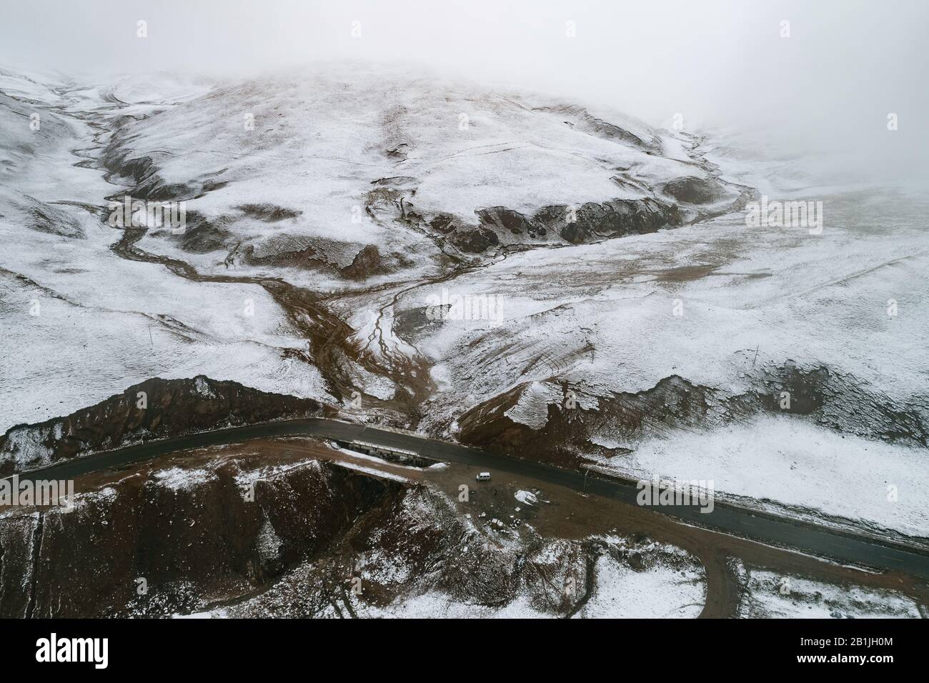 Country road winding through a valley surrounded by snowy mountains ...