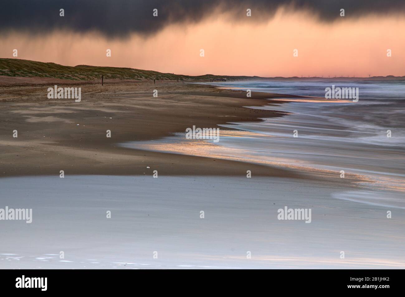 rain clouds above the North Sea beach at sunset, Netherlands, Den ...