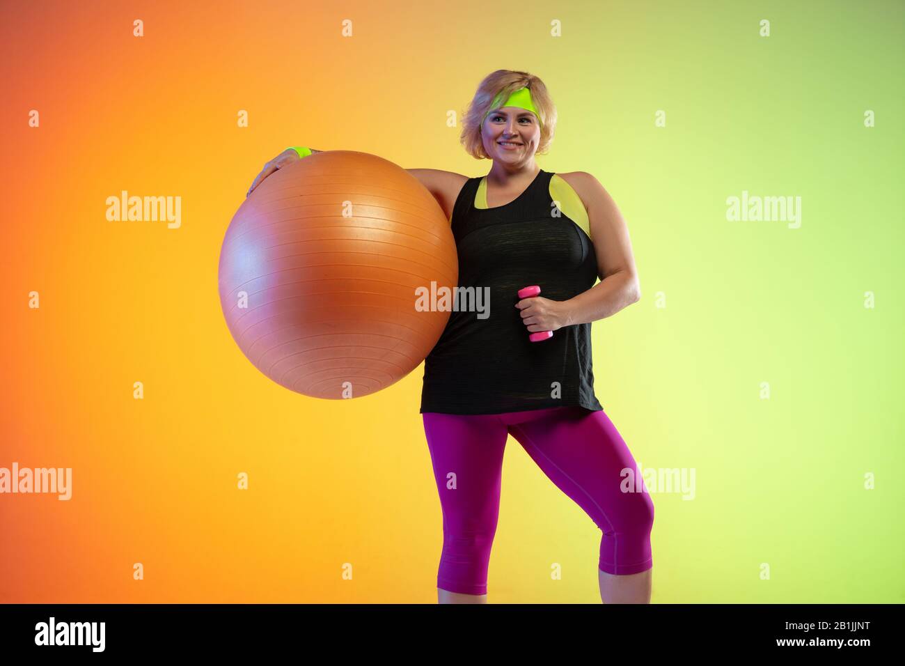 Young caucasian plus size female model's training on gradient orange ...