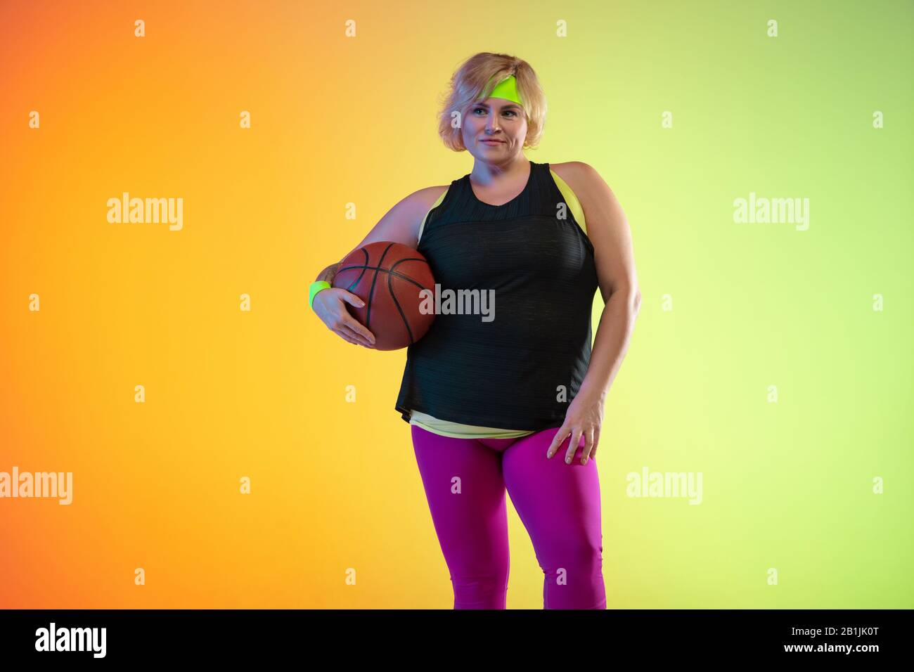 Young caucasian plus size female model's training on gradient orange ...