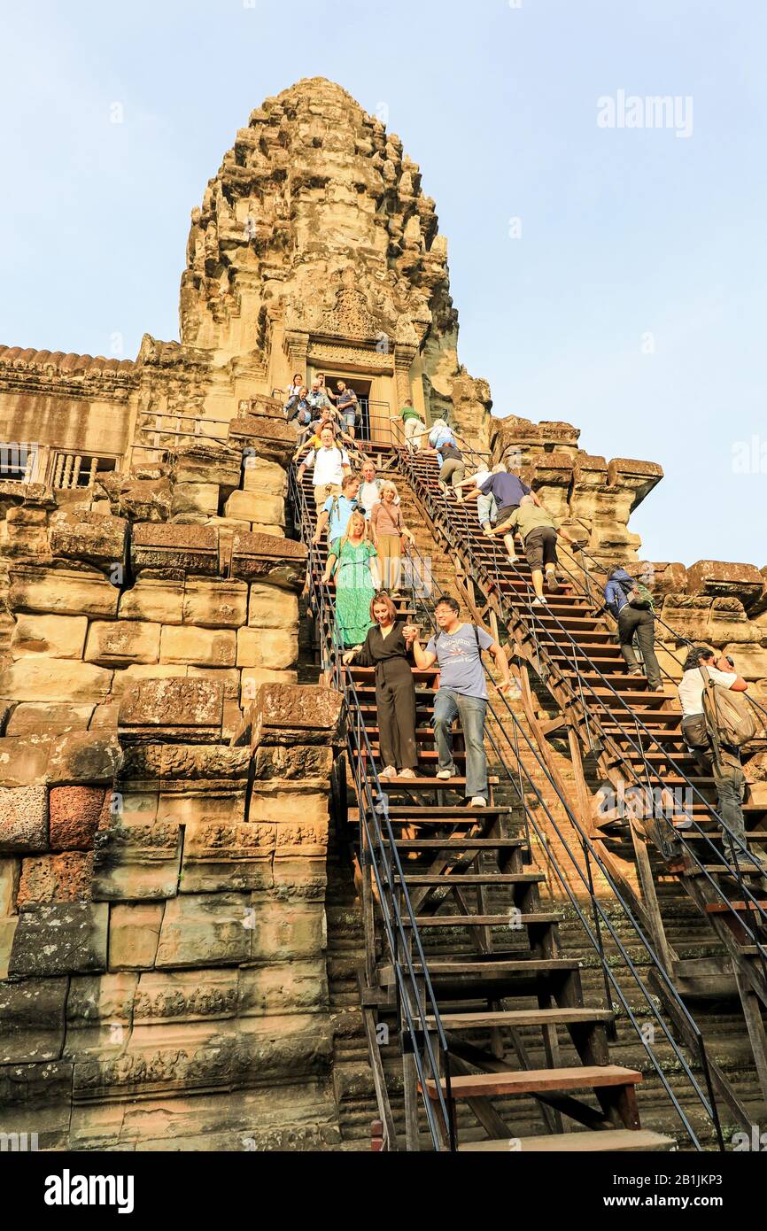 Tourists climbing steps up a tower at the Angkor Wat temple complex ...