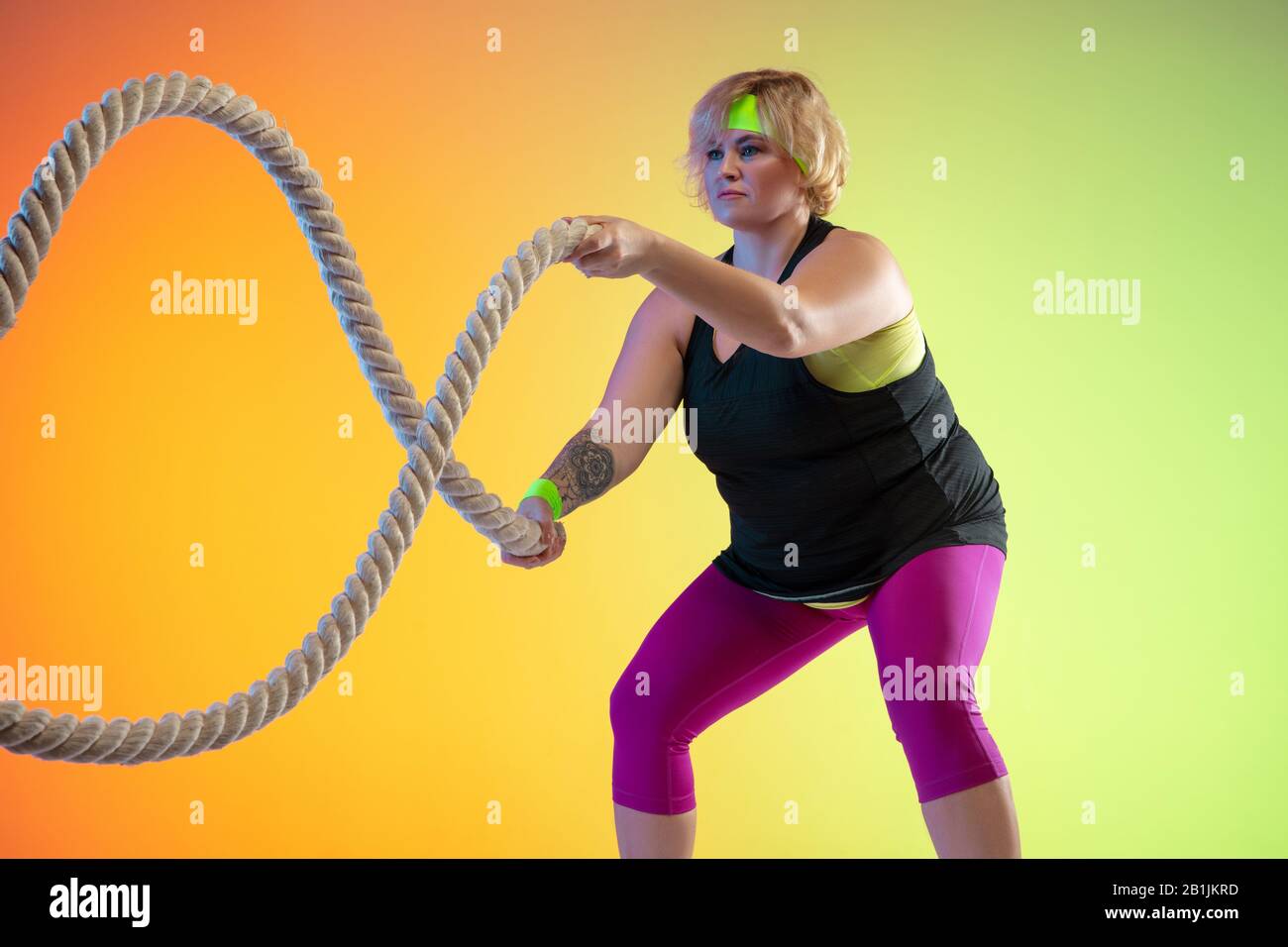 Young caucasian plus size female model's training on gradient orange ...