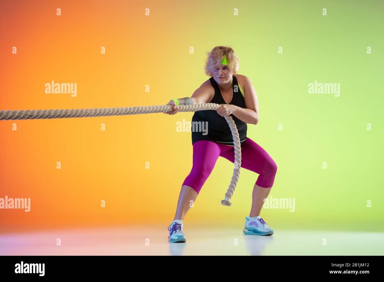 Young caucasian plus size female model's training on gradient orange ...