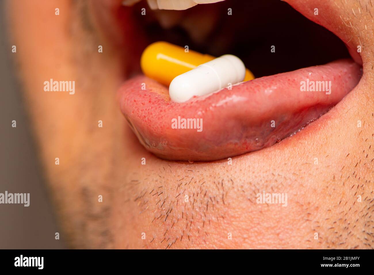 Man taking two pills yellow and white as a medicine Stock Photo - Alamy