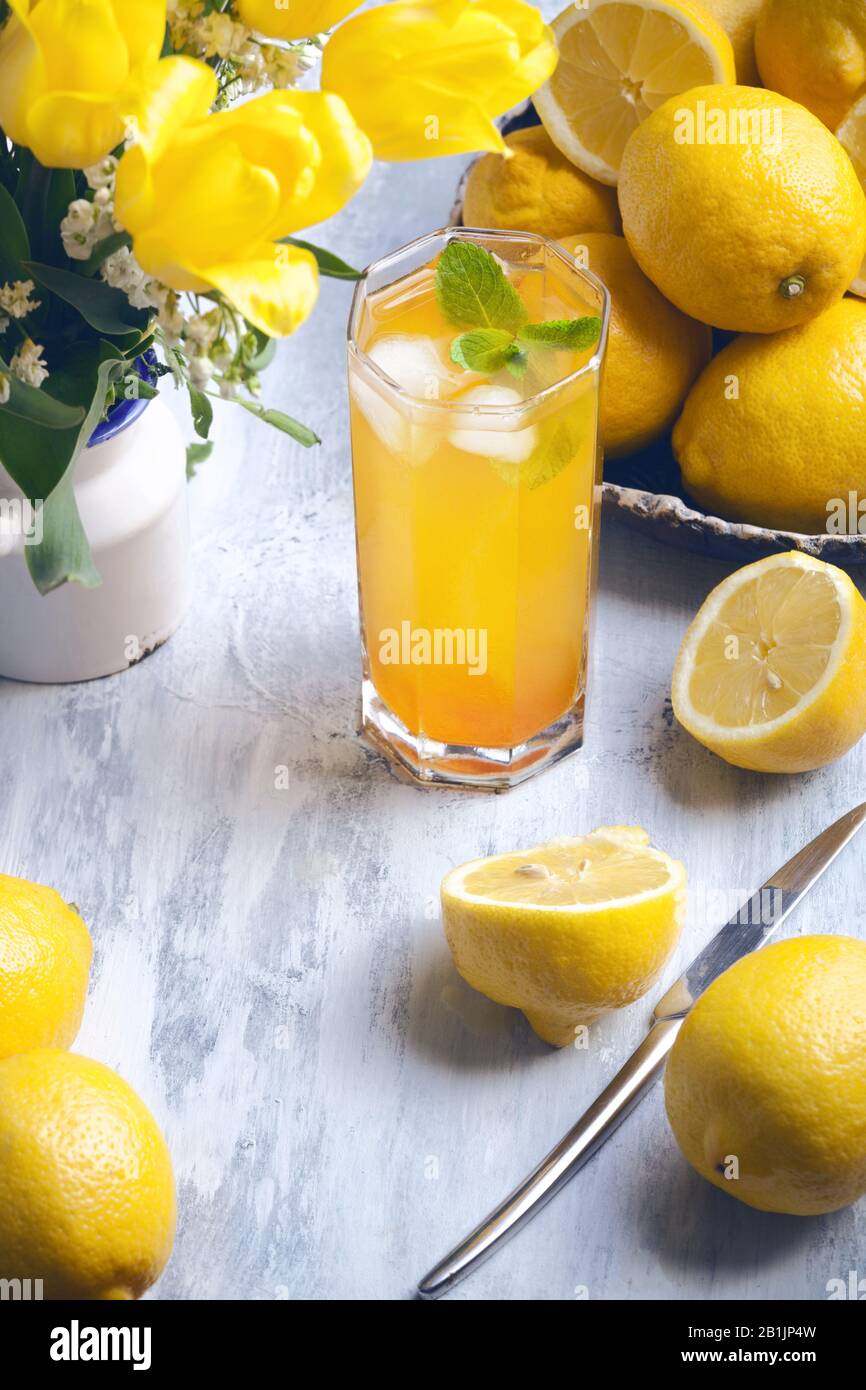 citrus lemonade with lots of lemons, mint and flowers on wooden table ...