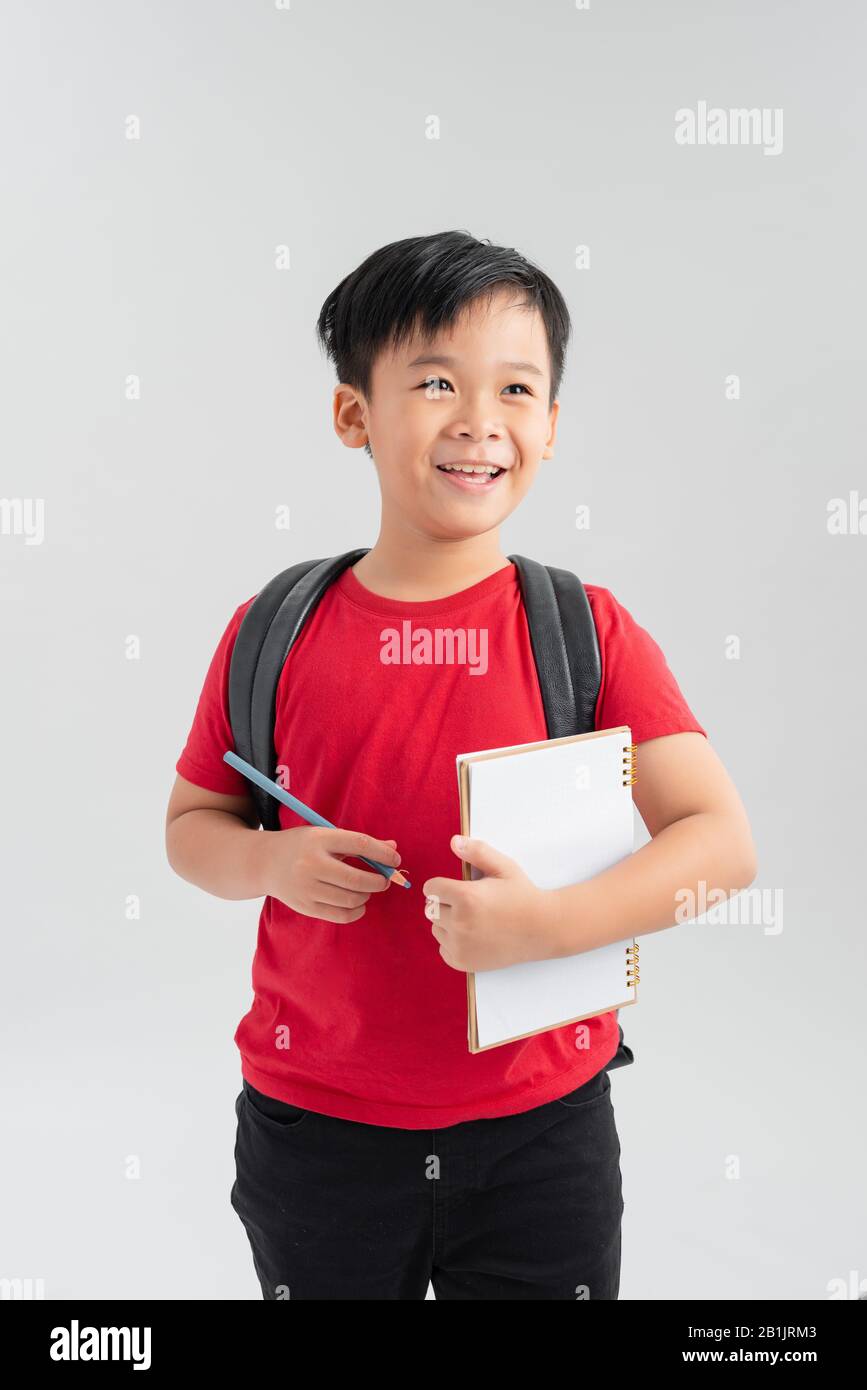 Young asian school boy writing in notepad with backpack on white ...