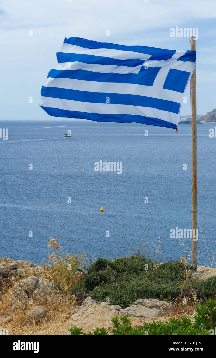 Mediterranean landscape with a Greek flag flying in the wind vertical ...