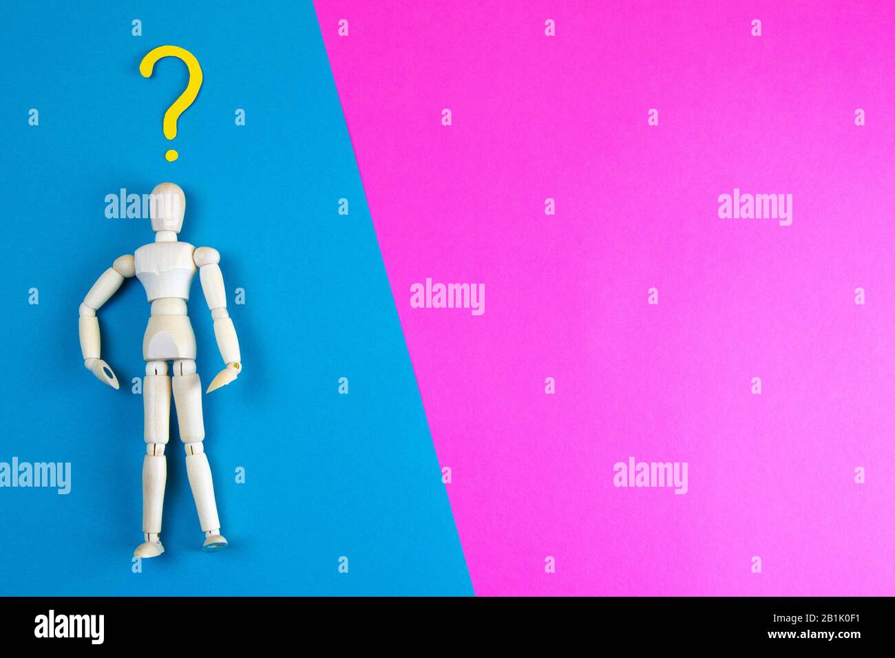 Wooden figurine of a man with question mark on a blue and pink ...