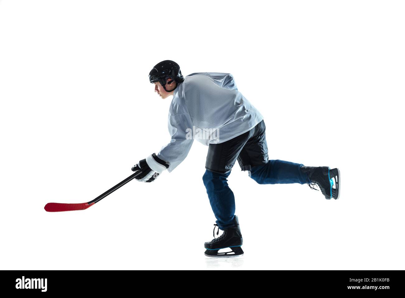 Running. Young male hockey player with the stick on ice court and white ...
