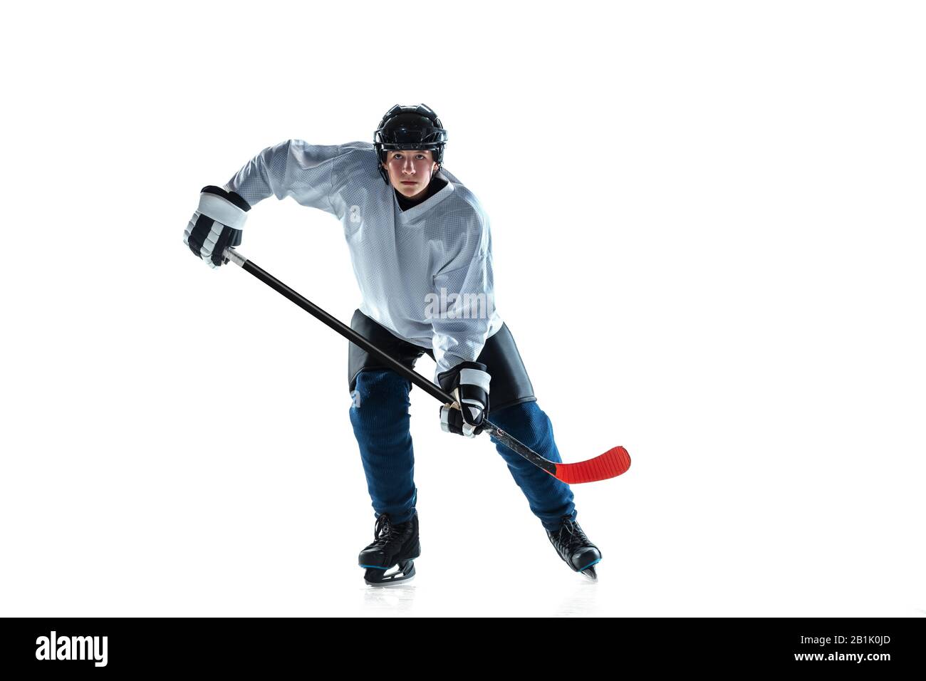 Running. Young male hockey player with the stick on ice court and white ...