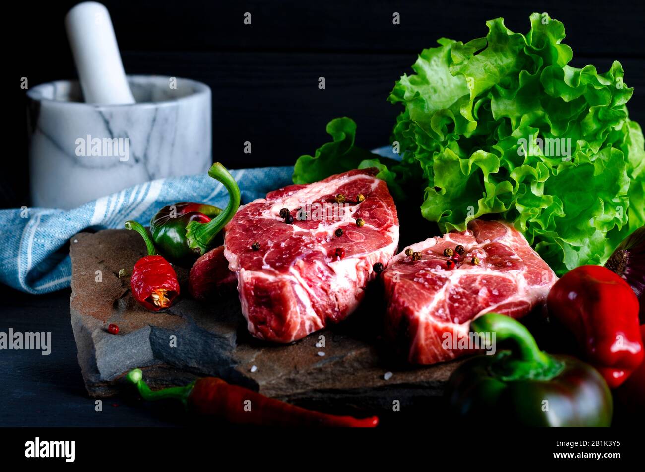 Meat concept. Meat steaks are ready to cook with vegetables lying on ...