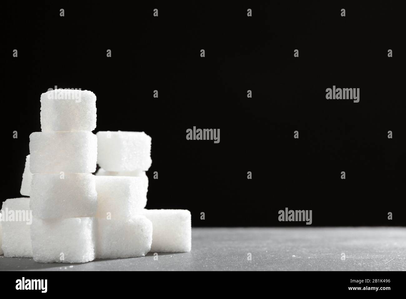 Sugar lumps piled up together against a black background Stock Photo ...
