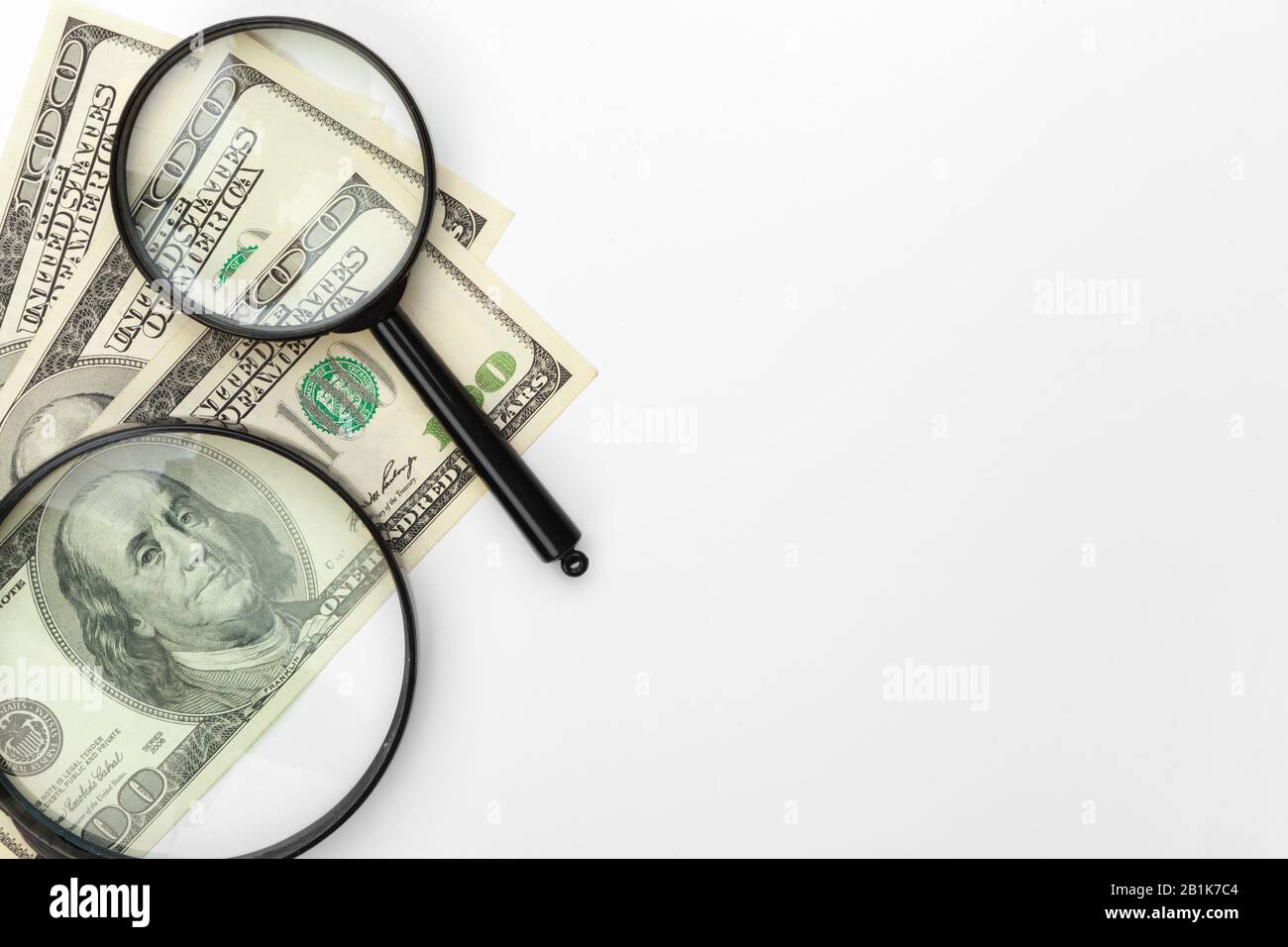 Magnifying glass and a pile of money Stock Photo - Alamy