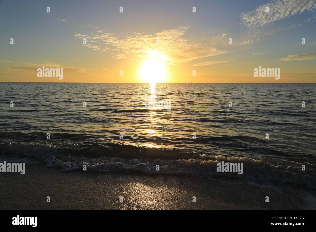 Sun setting over the water Stock Photo - Alamy
