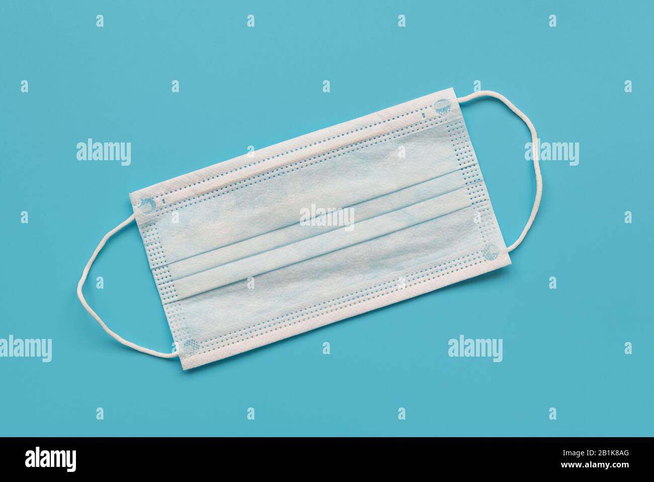 Surgical ear-loop mask on blue background. Top view. Protection concept ...