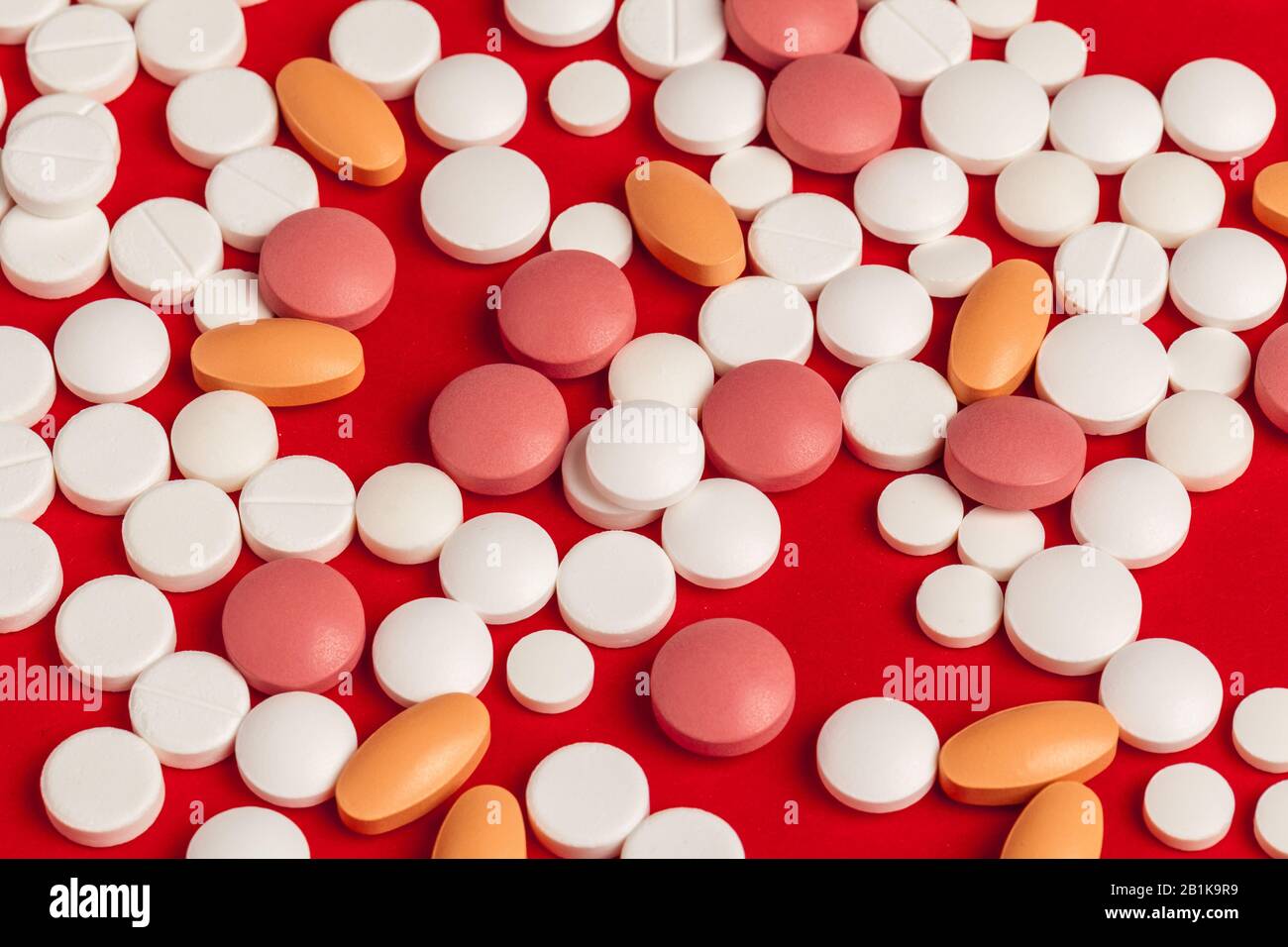 Many medicine pills close up on red background Stock Photo - Alamy