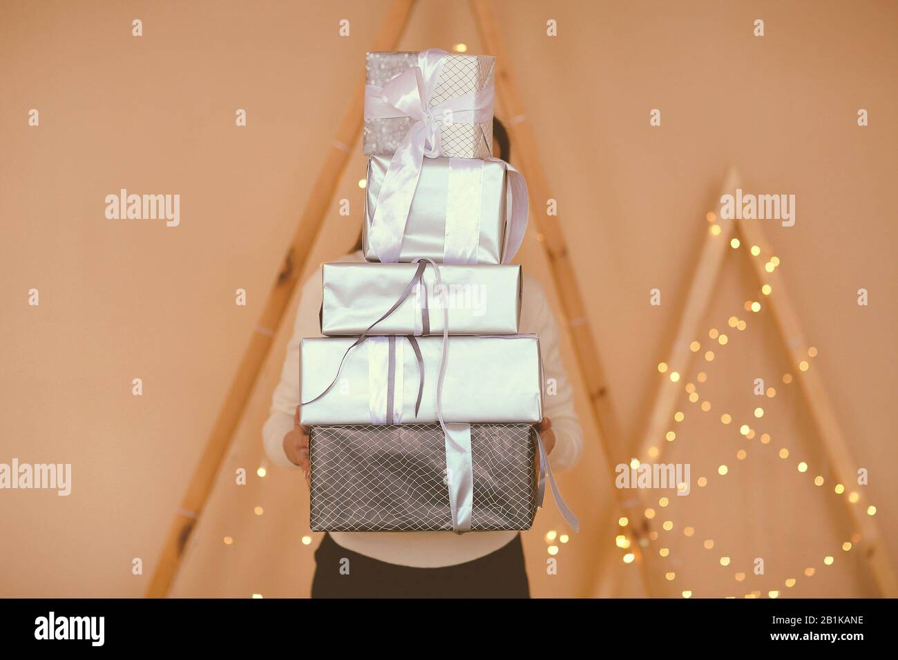 Female holding big stack of presents wrapped in brown paper with white ...