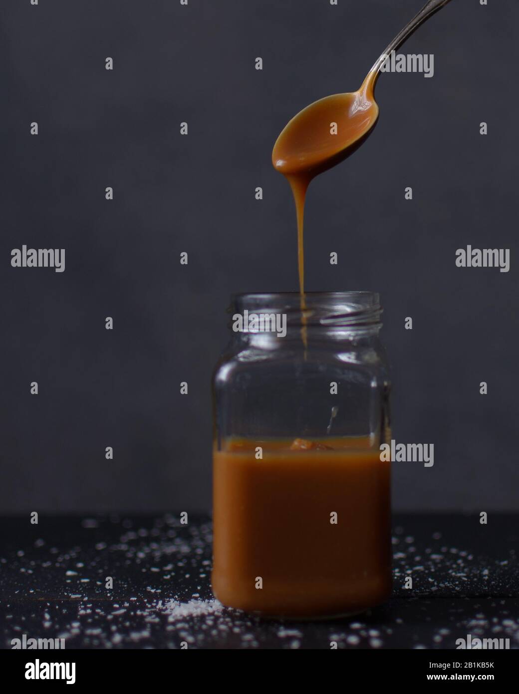 Salted caramel sauce dripping from a spoon into a glass jar, Caramel ...