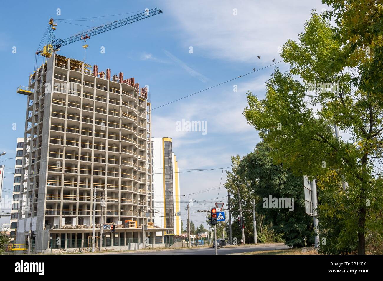 Concrete frame of tall apartment building under construction and tower ...