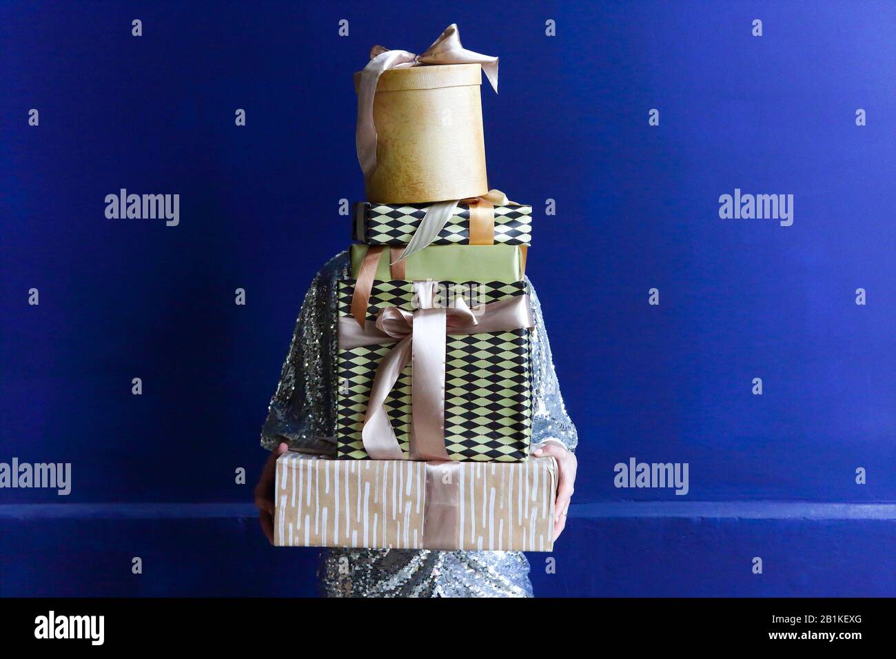 Female holding big stack of presents wrapped in golden paper with white ...