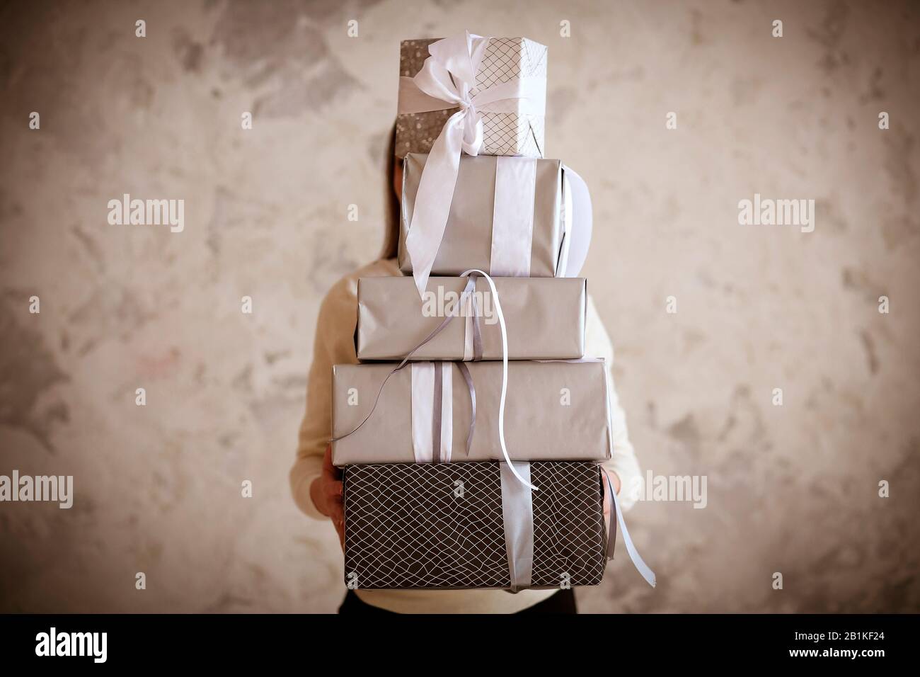 Female holding big stack of presents wrapped in brown paper with white ...
