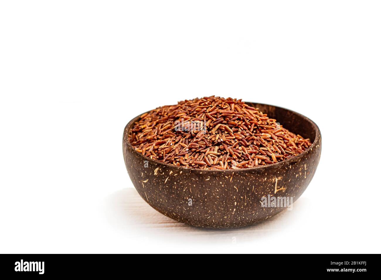 Red rice in a bowl of coconut on a white background Stock Photo - Alamy