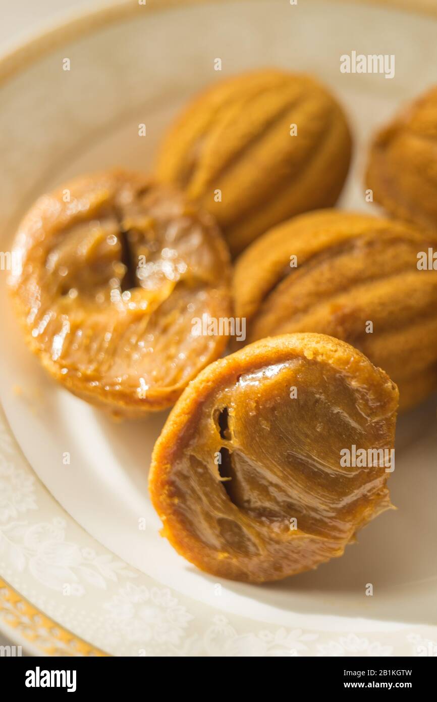 Walnut shaped cookies with condensed milk in white saucer. One open in ...