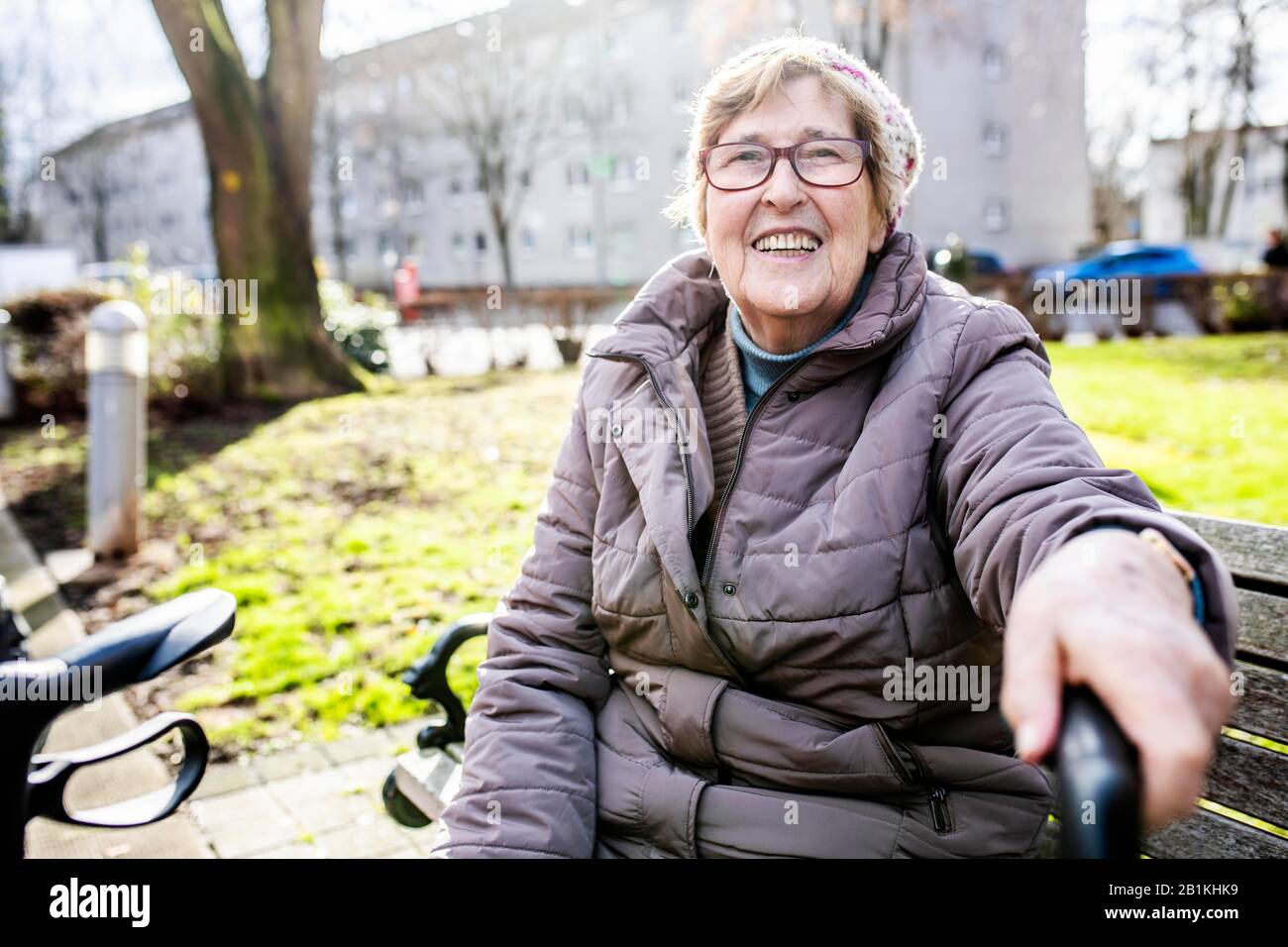 Senior citizen sitting on a bench in front of a residential building ...