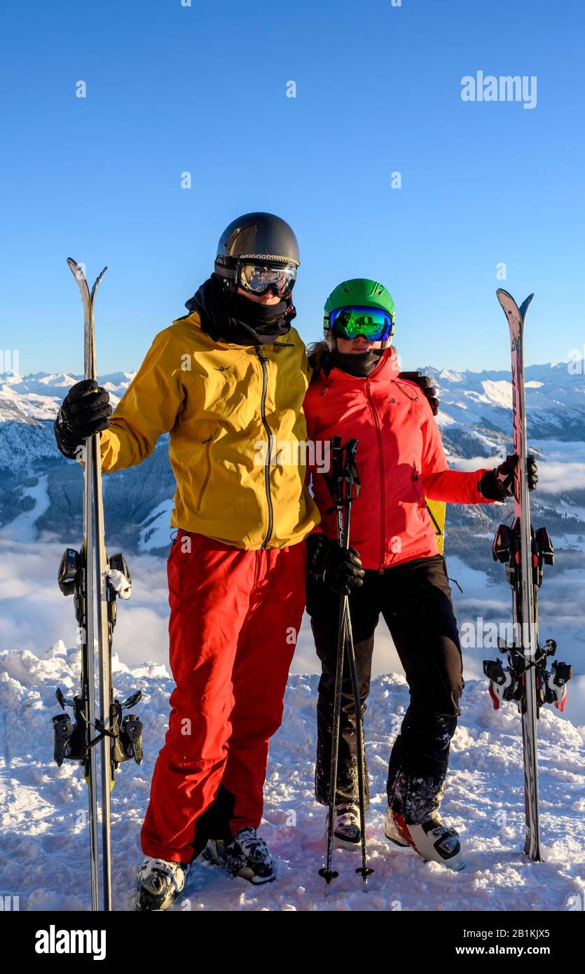 Two skiers with ski helmets and skis standing on the ski slope in front ...