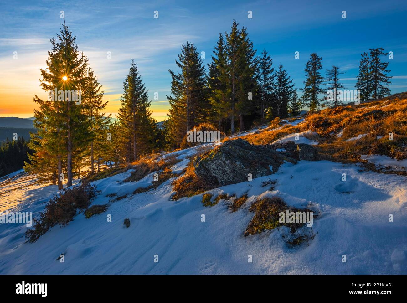 Snow-covered alpine pasture at sunrise with forest, sun star, summer ...