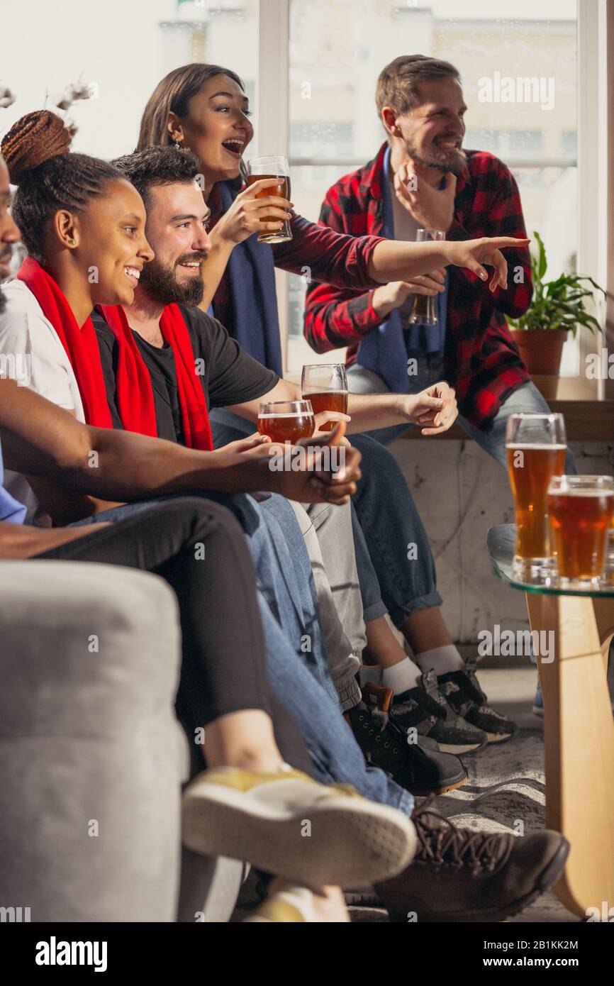 Excited group of people watching football, sport match at home ...