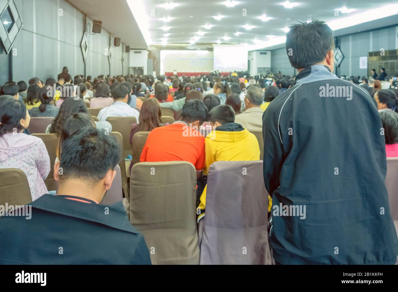 Backside view of spectators sitting in a gathering in the back of ...