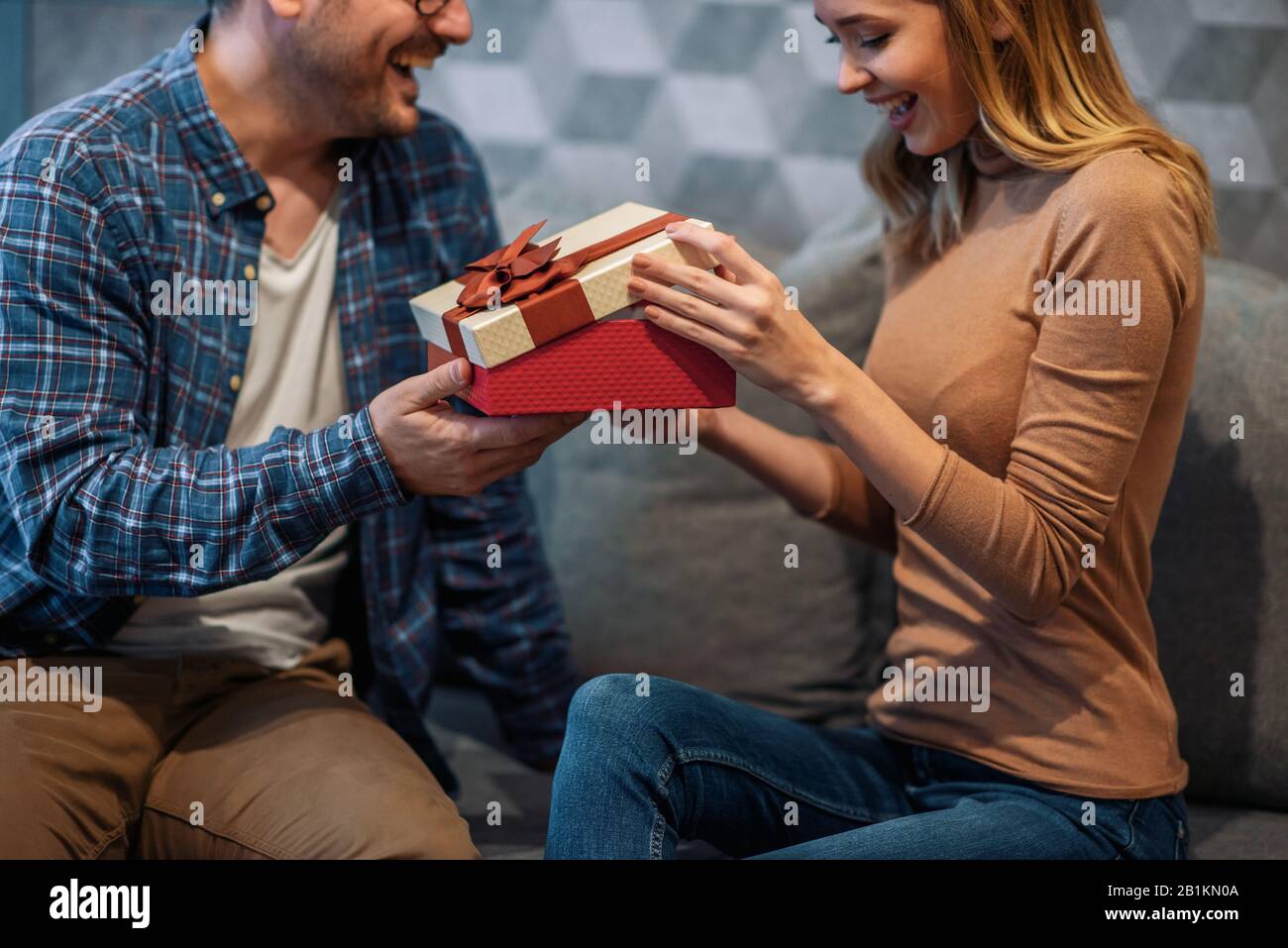 Happy young couple celebrating at home.Man is giving his girlfriend a ...